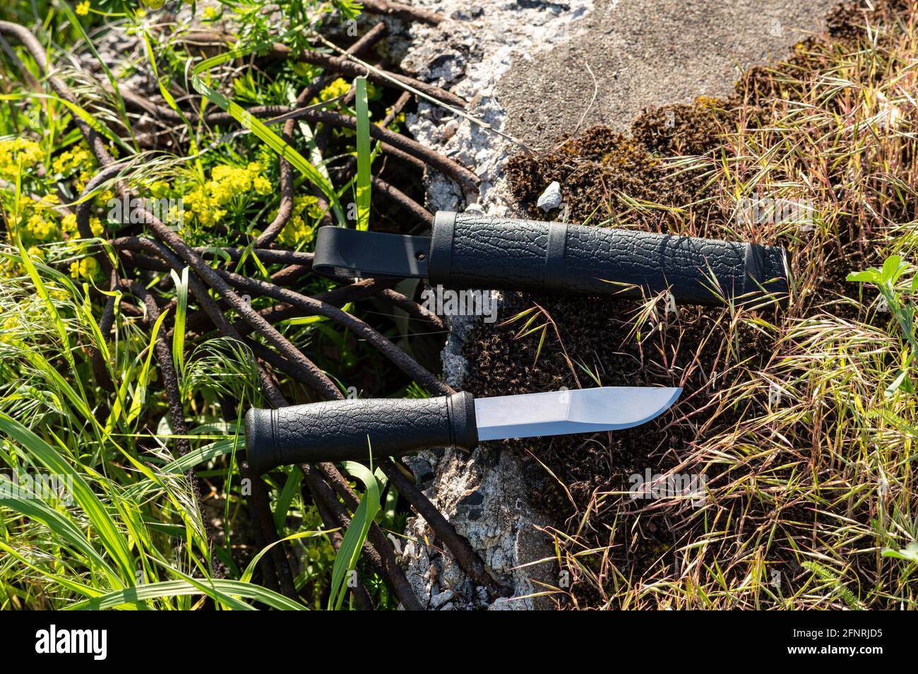 Fixed blade knife with black handle. Concrete knife and iron rods ...
