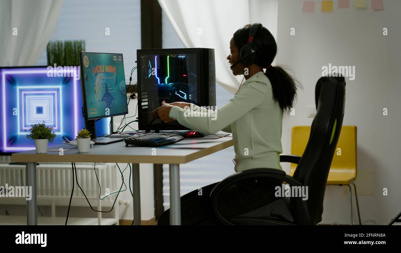 Winner black gamer sitting on gaming chair playing space shooter video ...