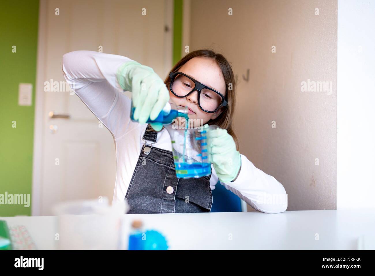 pretty young schoolgirl sitting on her desk in room at home ...