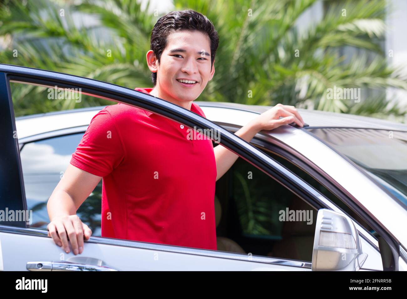 Asian man standing in front of new car Stock Photo - Alamy
