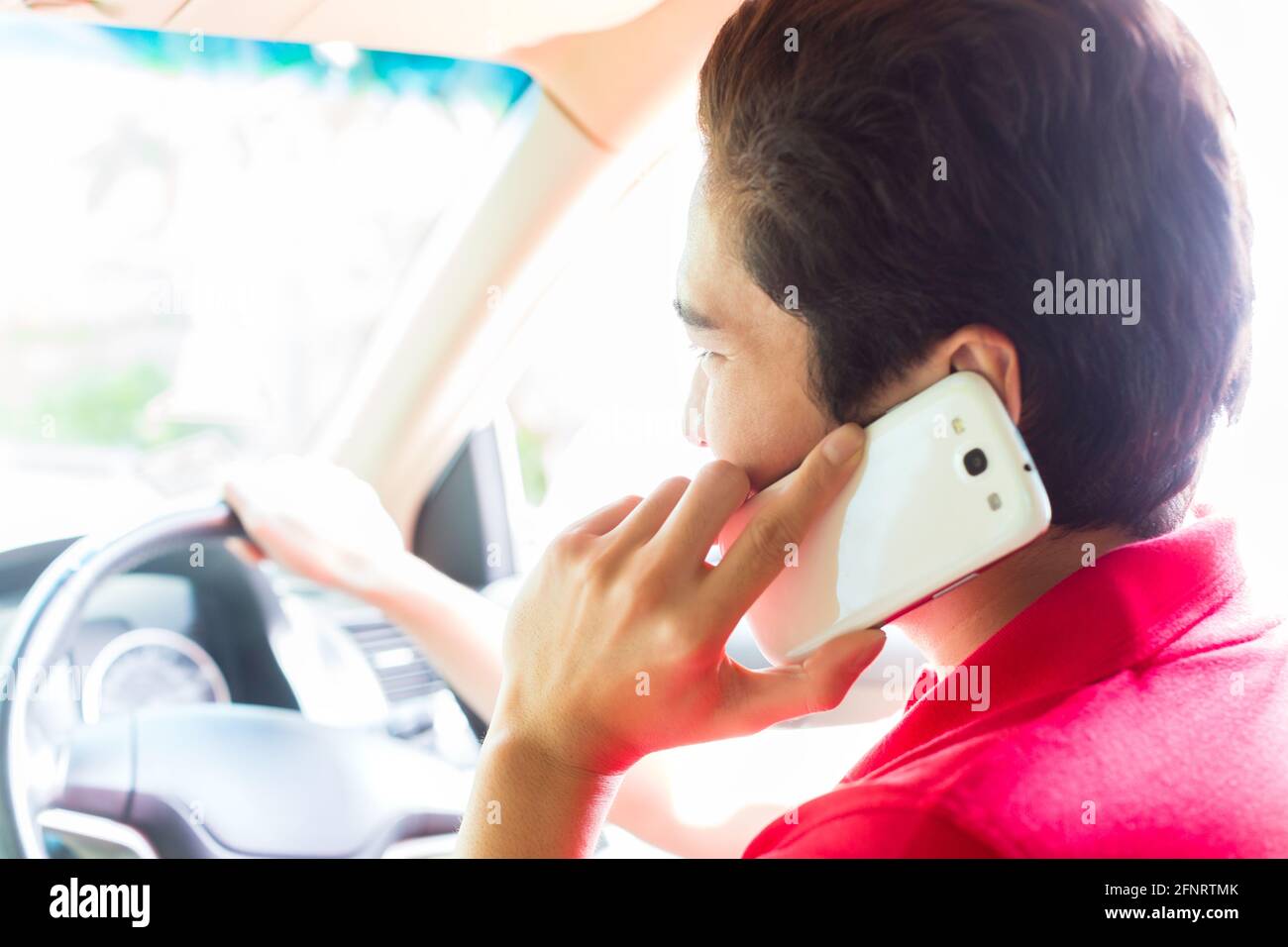 Asian young man telephoning with mobile phone or smartphone while ...