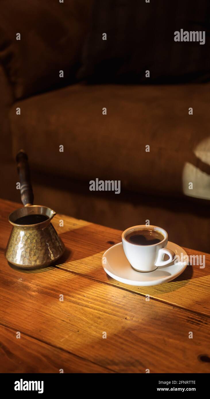 Small demitasse cup of Greek coffee on a saucer and a briki sitting on ...