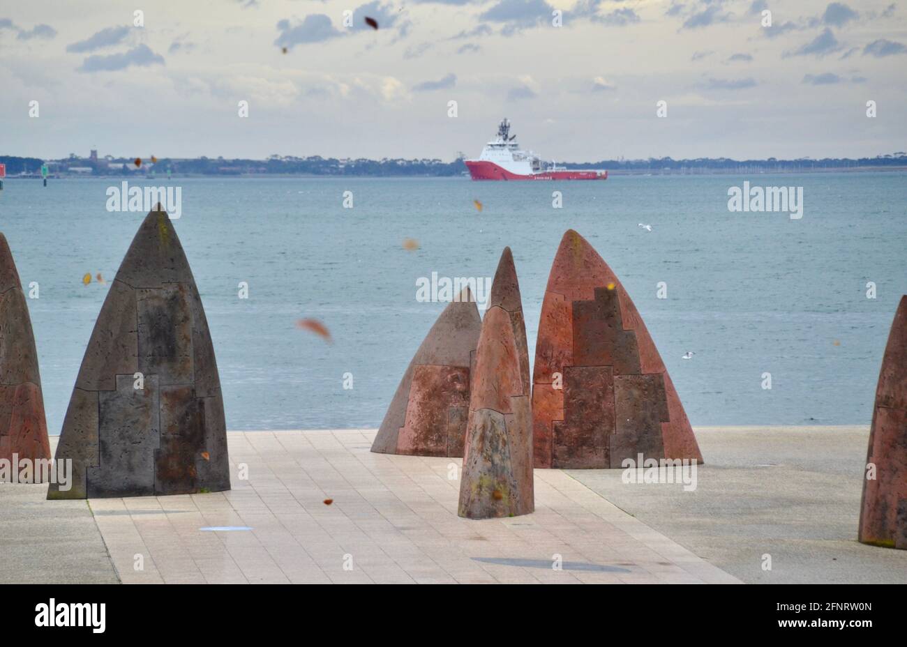 Stone shark fins in the Geelong waterfront park with a ship in the ...
