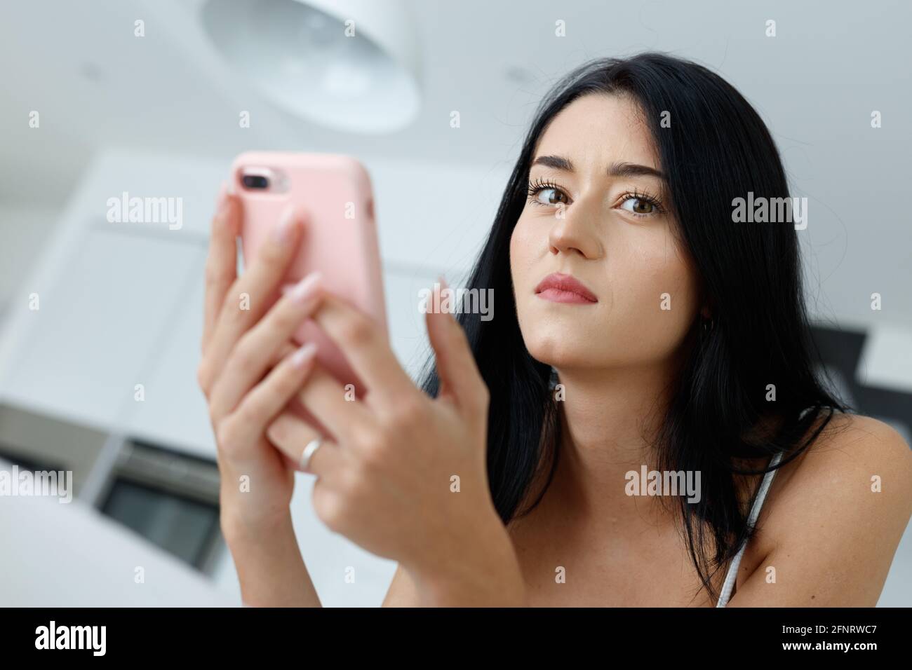 Startled young woman looking down at the camera wide eyed as she ...
