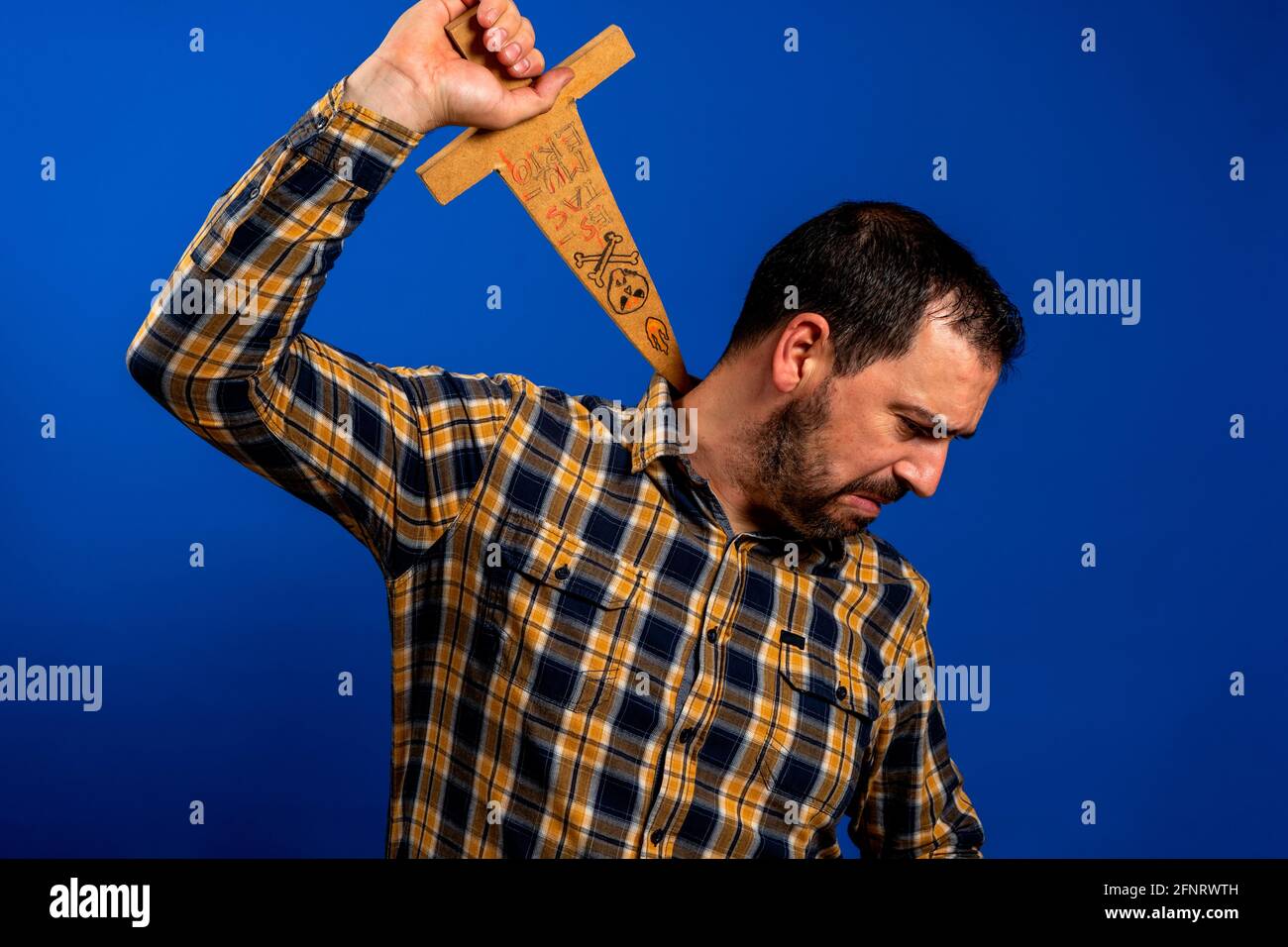 Man in a yellow plaid shirt scratching his back with a wooden sword ...