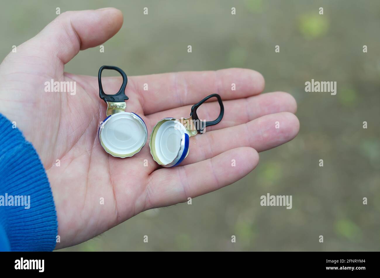 Hand and ring pull beer caps. Two beer stoppers lie in a male palm ...