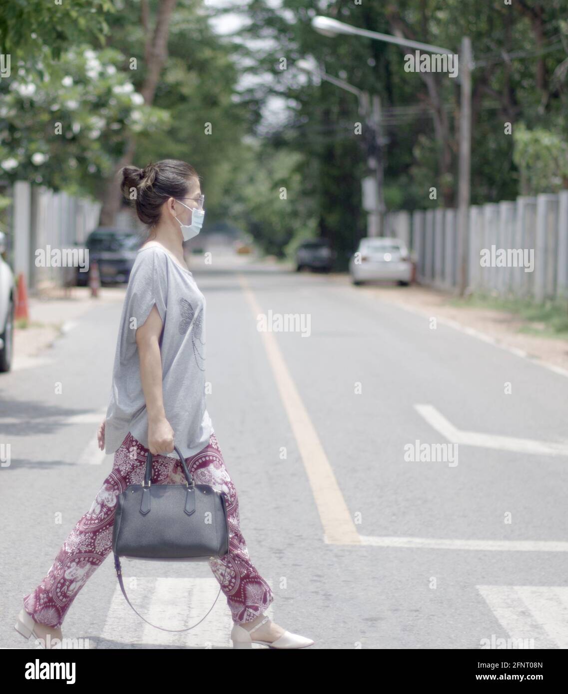 A woman walking across a crosswalk Stock Photo - Alamy