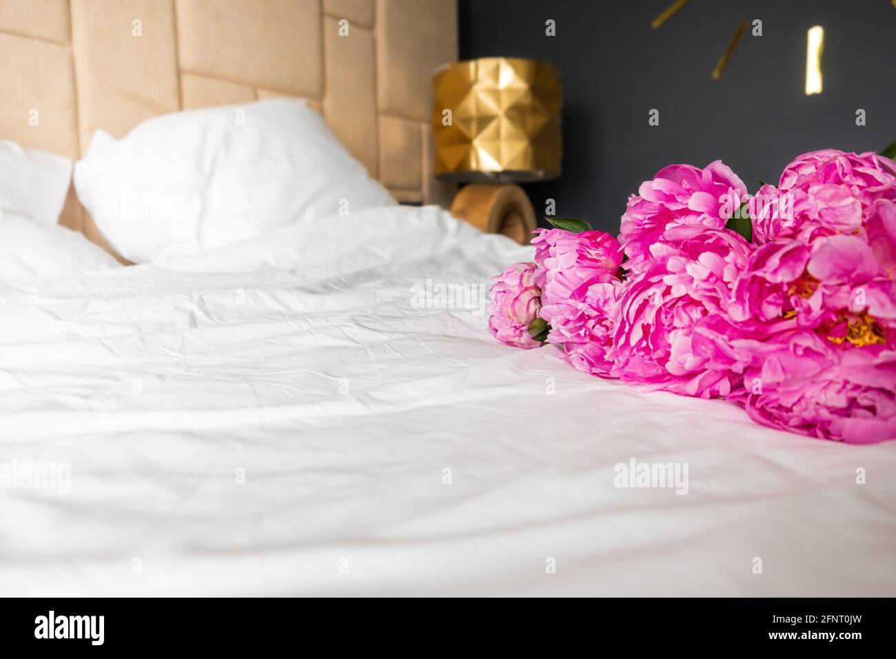Beautiful big pink peonies lying on the bed. Fresh spring flowers. Copy ...