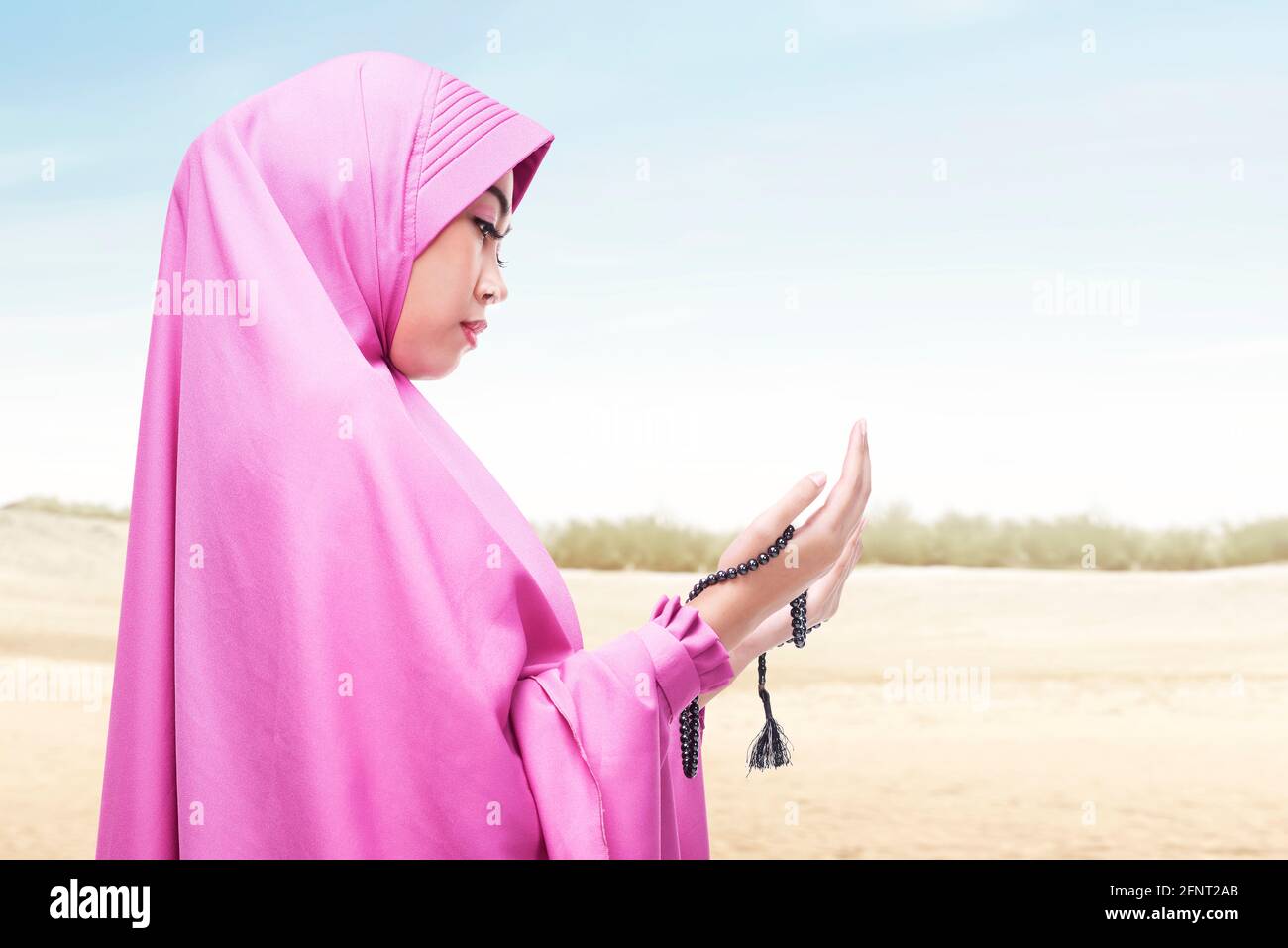 Asian Muslim woman in veil praying with prayer beads on her hands on ...