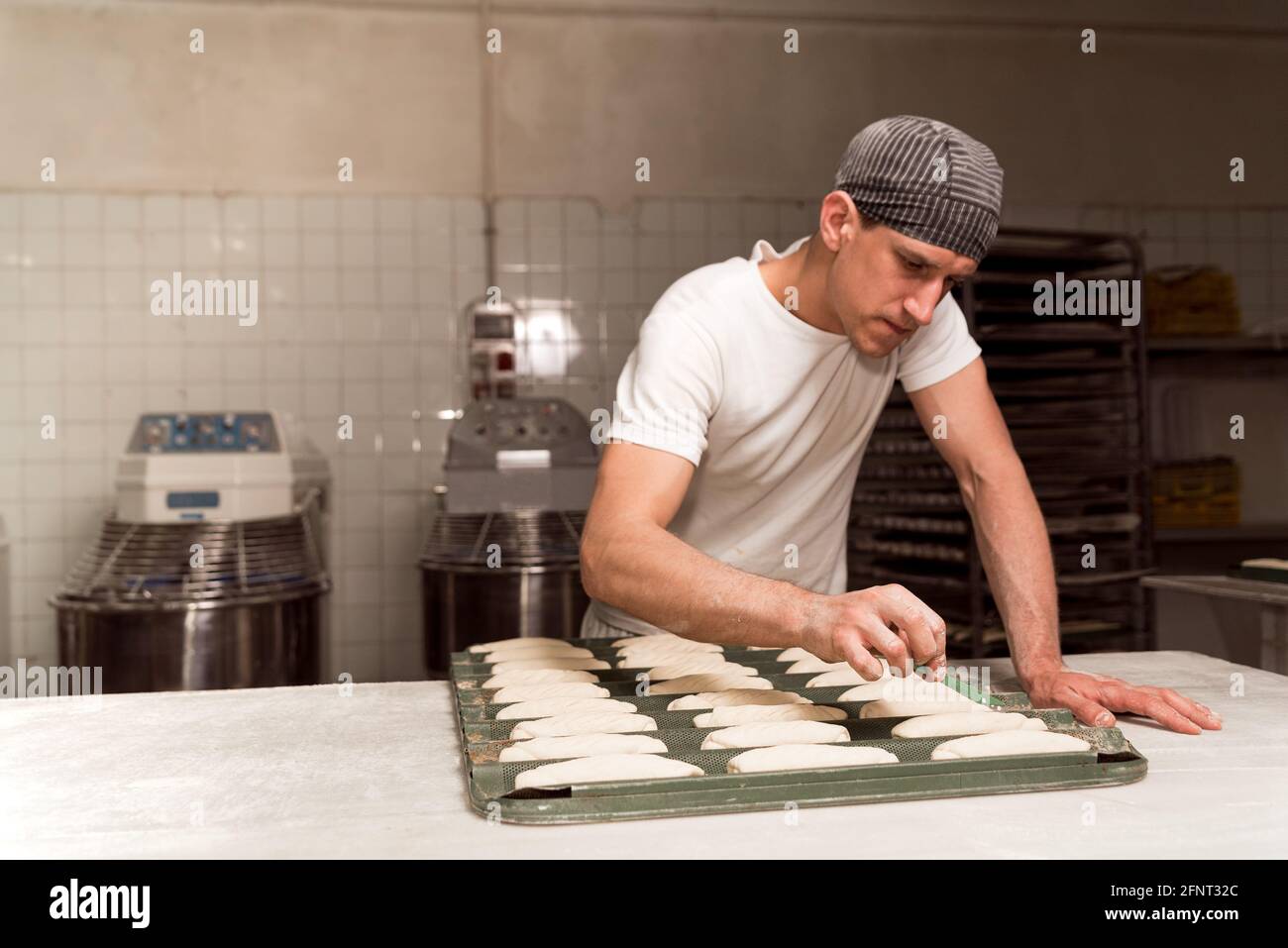 close up of baker cutting and decorating fresh bread dough before ...
