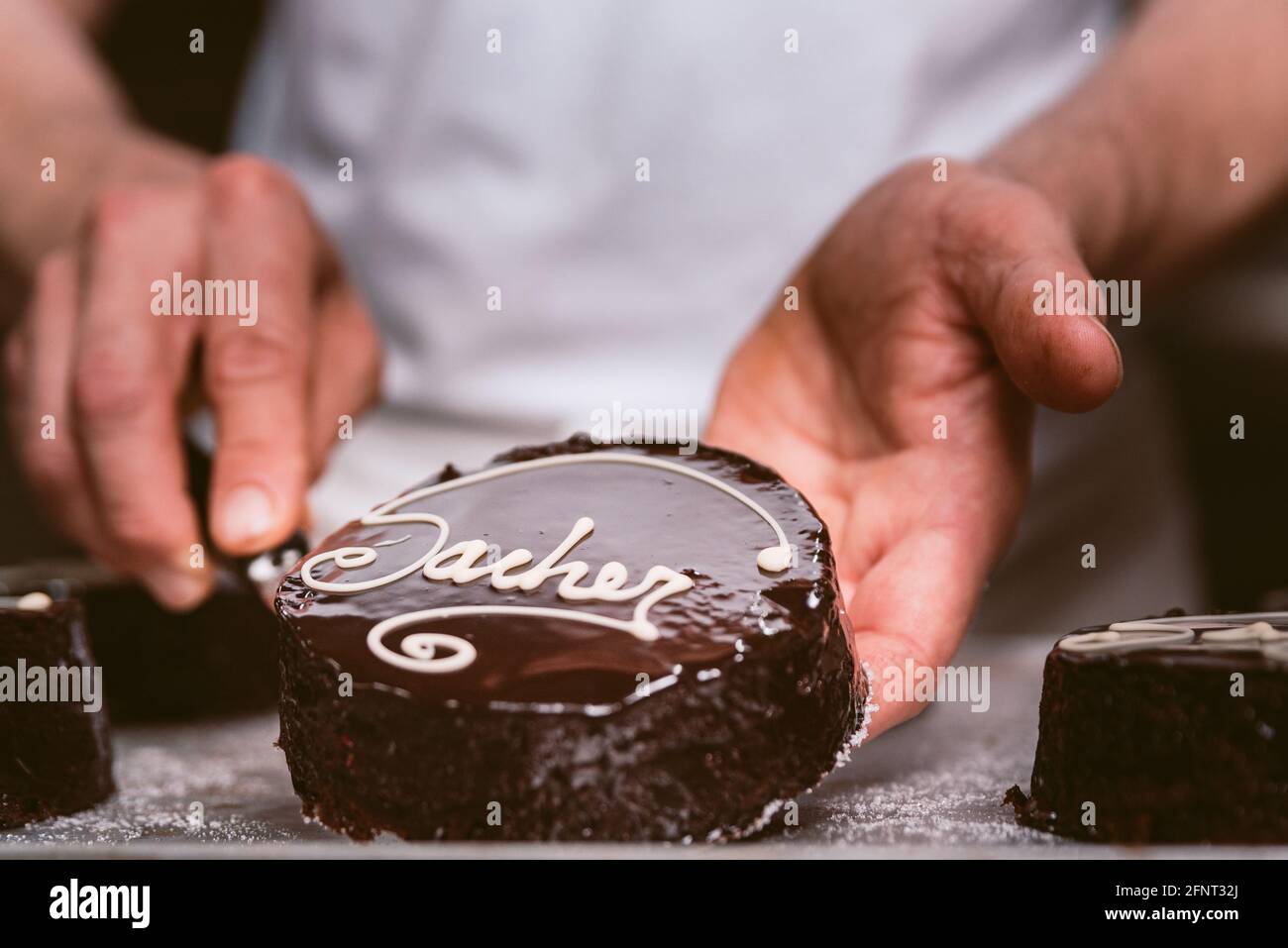 hands holding chocolate sacher cake in bakery shop. pastry chef hands ...