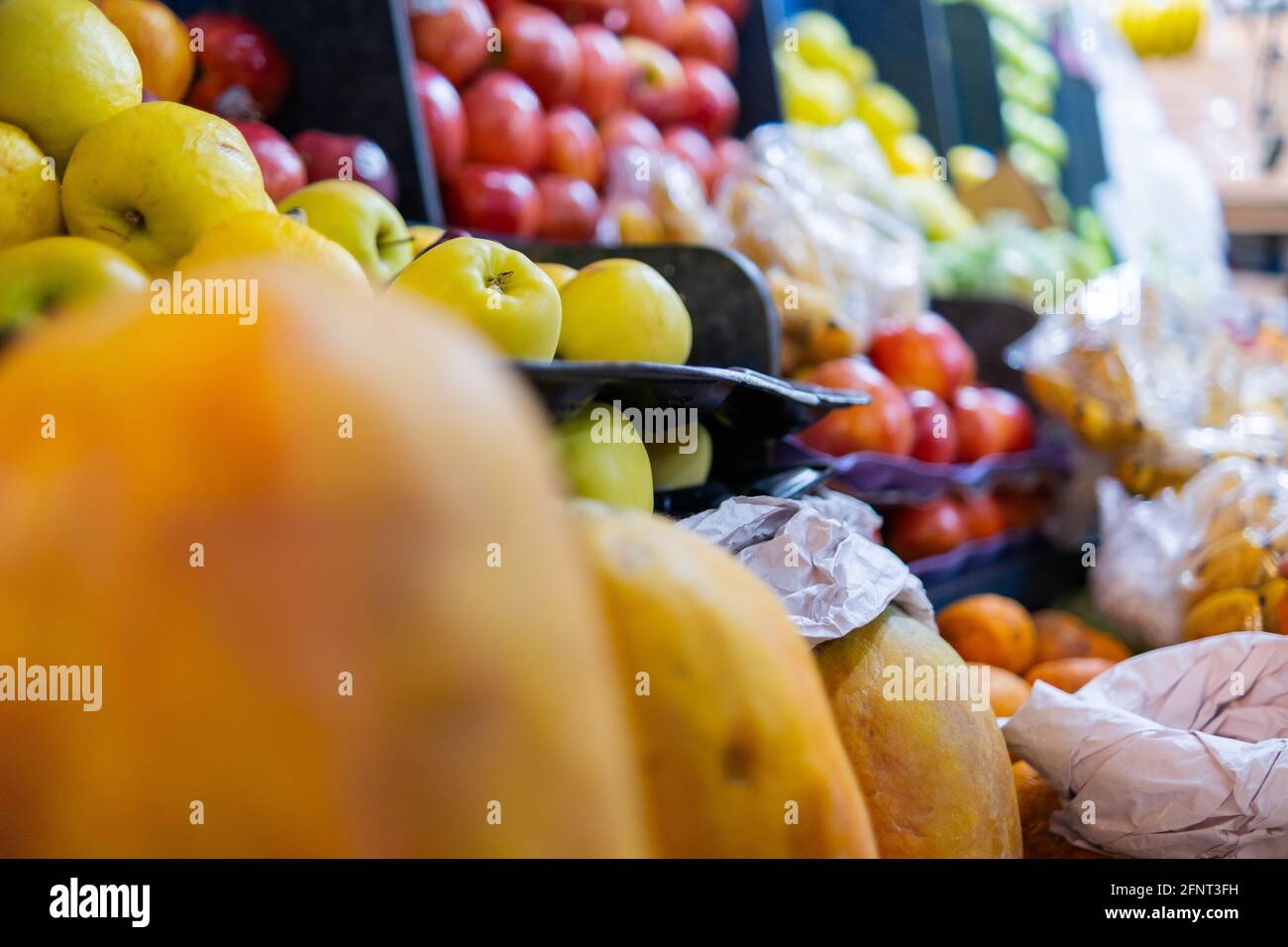 Colorful fruit stand with papayas, apples, small bananas, and more ...