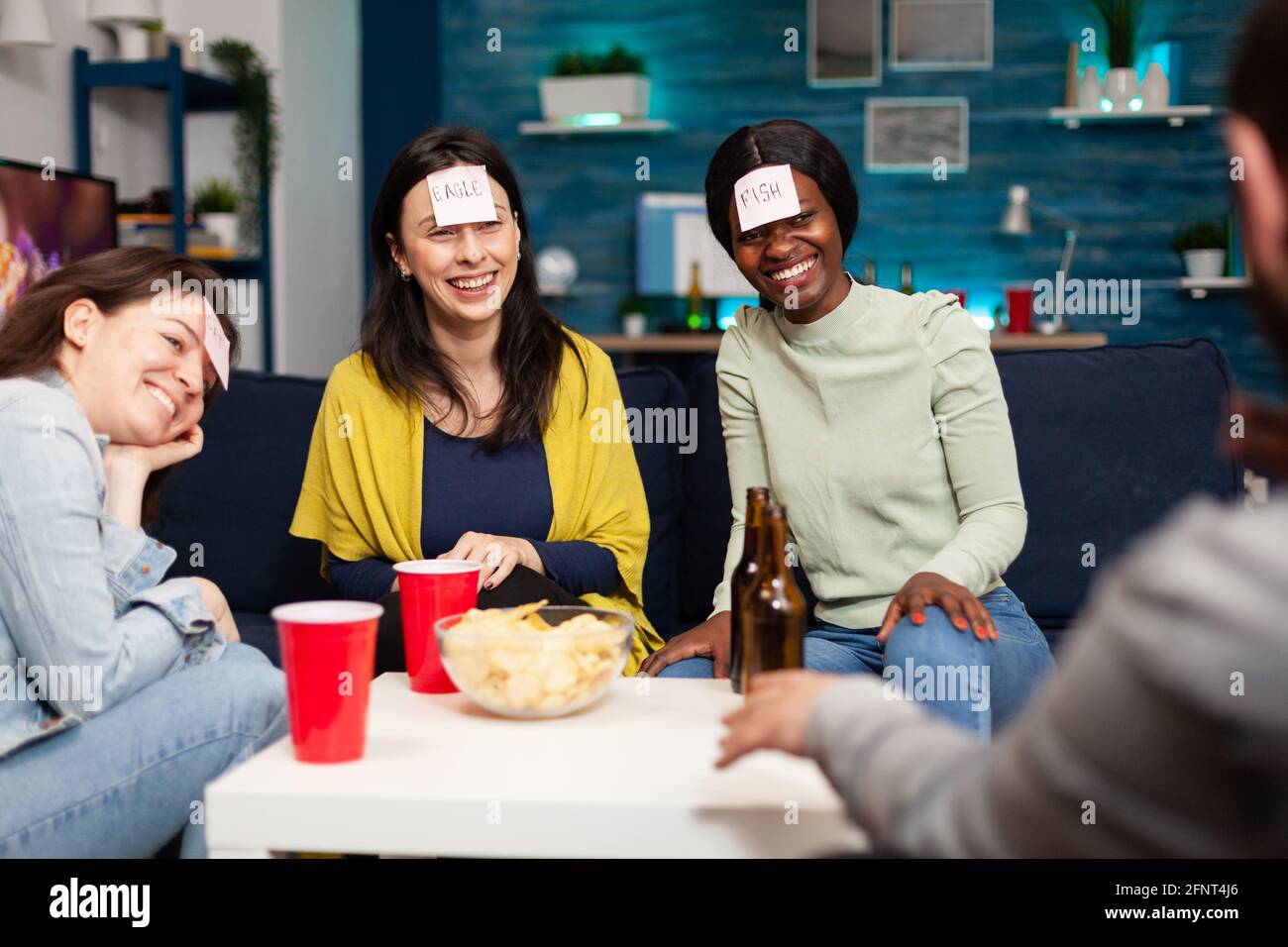 Mixed race friends playing Guess who game with sticky papers attached ...