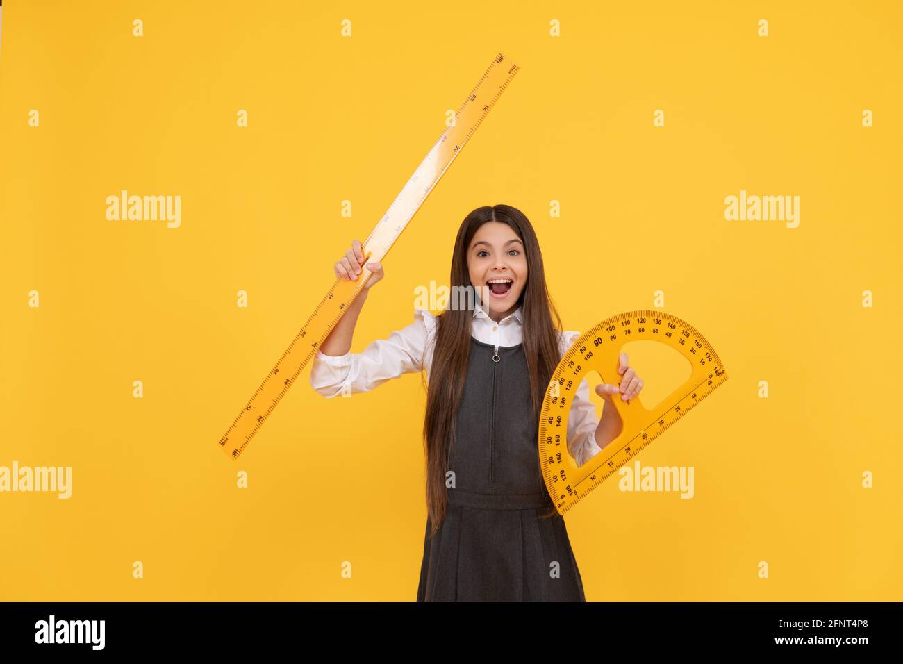 happy kid hold math protractor and ruler in school on yellow background ...