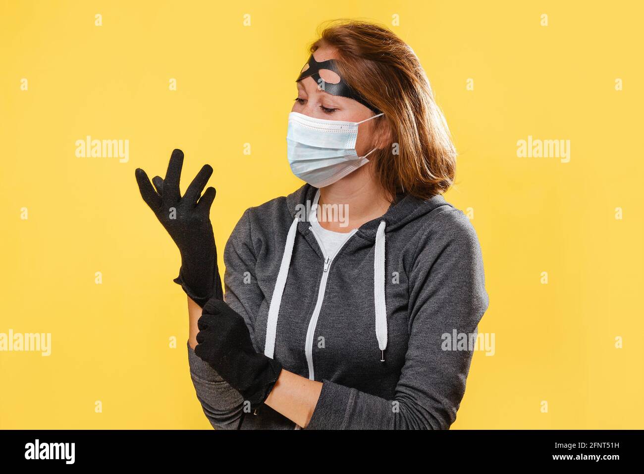 New normal. A female hacker in a black hat and protective mask, wearing ...