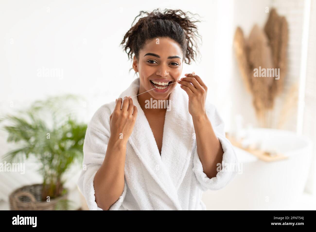 African American Woman Flossing Teeth Smiling To Camera In Bathroom ...