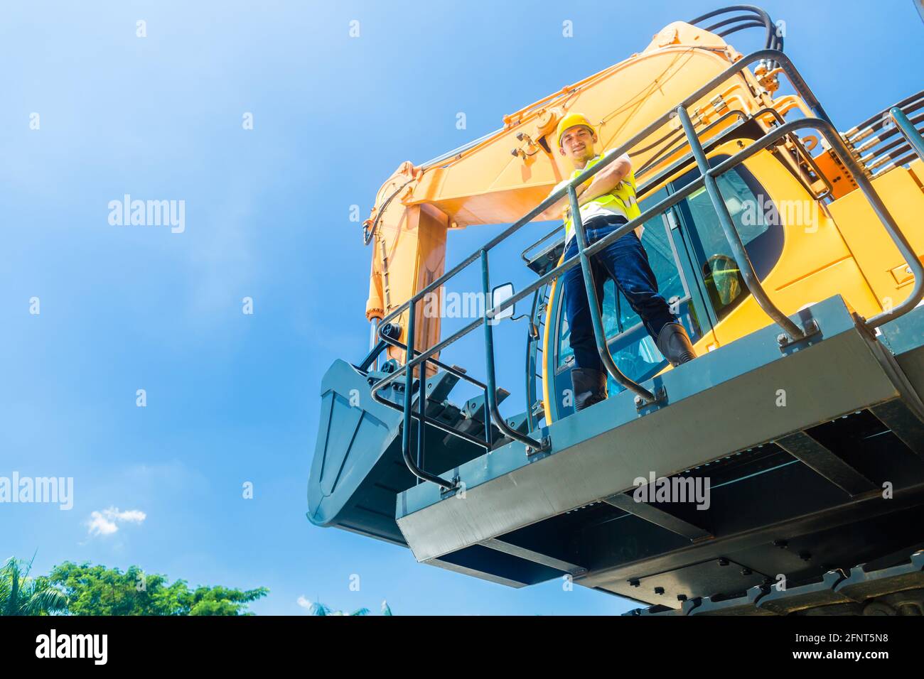 Asian driver standing on construction machinery on building site Stock ...