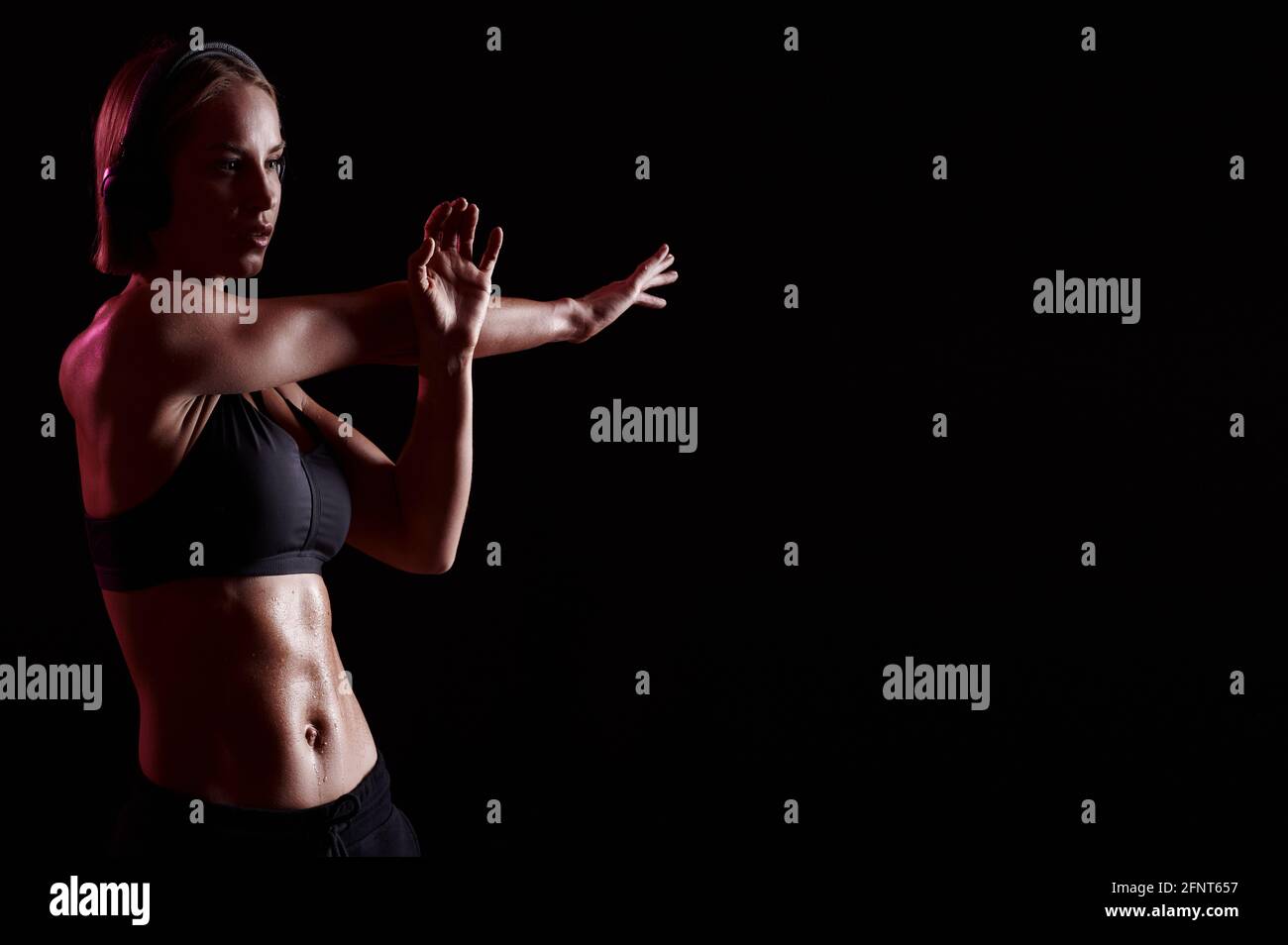 Slim strong muscular sportswoman stretching before workout and listen ...