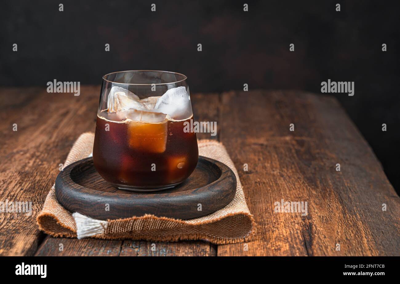 Iced coffee in a clear, steamed glass on a brown background. Side view ...