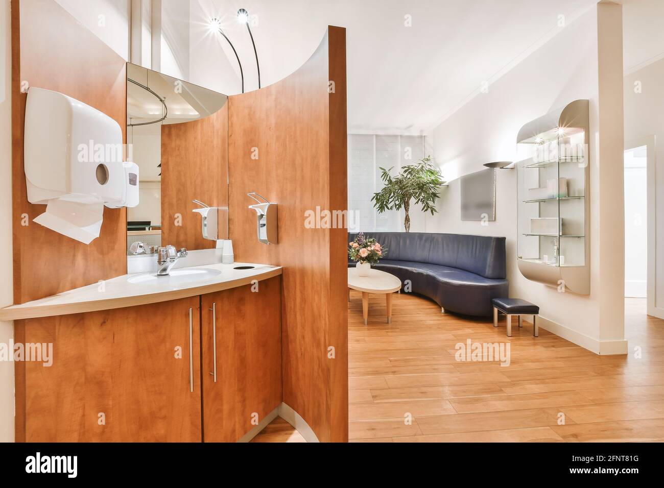 Sink with mirror and toiletries located in front of partition in lobby ...