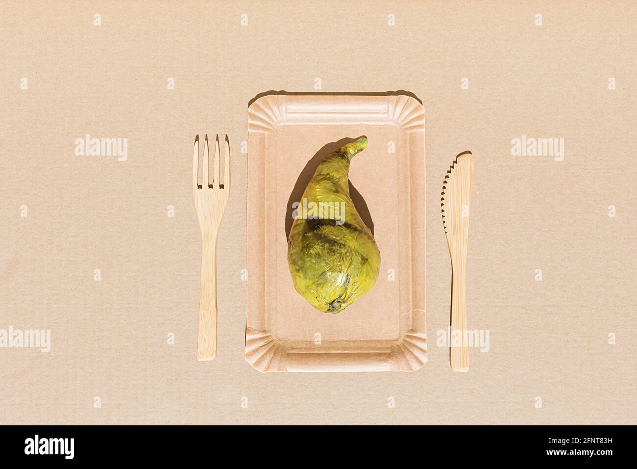 Pear wrapped in polyethylene plastic on the beige paper background ...