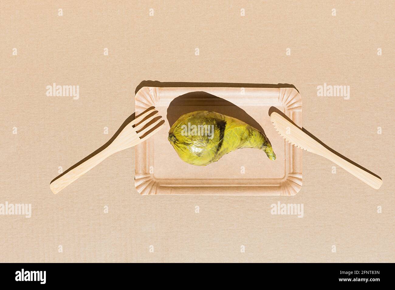 Pear wrapped in polyethylene plastic on the beige paper background ...