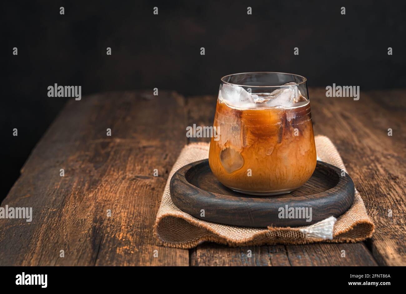 Iced coffee with milk on a brown wooden background. Side view, copy ...
