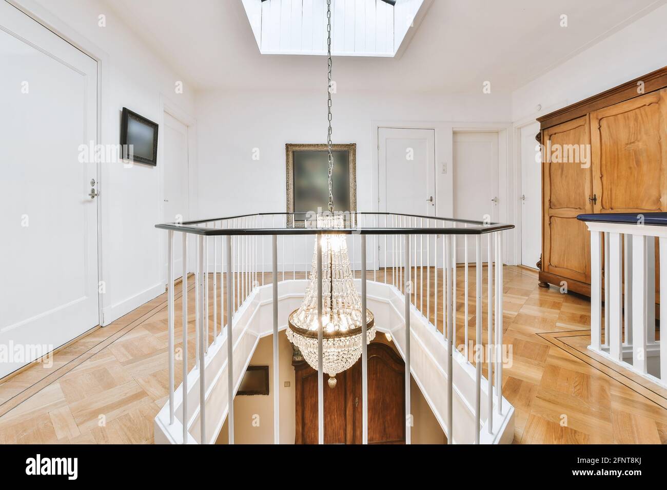 Posh crystal chandelier hanging on chain near banister on upper floor ...