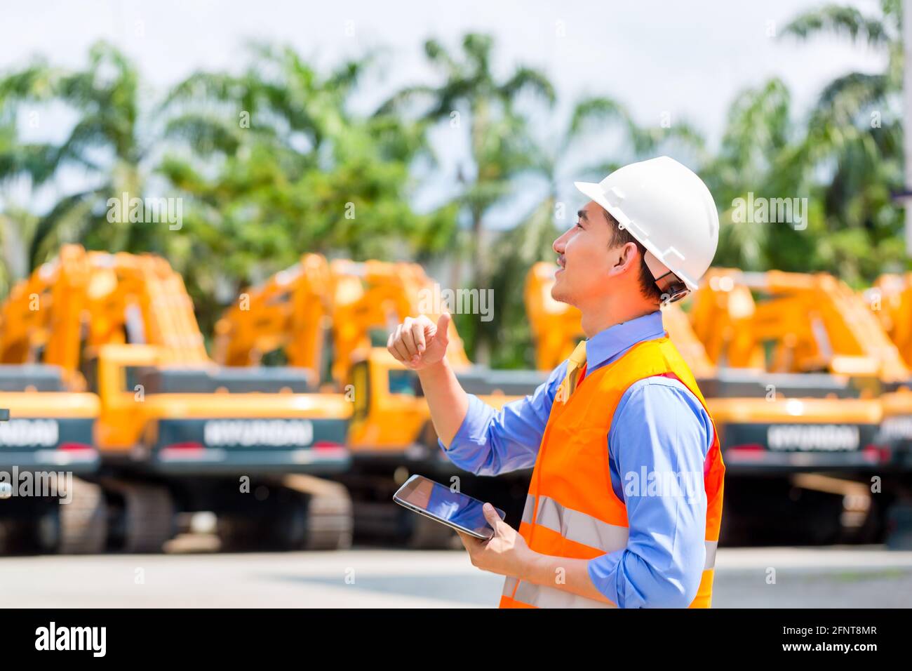 Asian engineer checking plans on construction site Stock Photo - Alamy