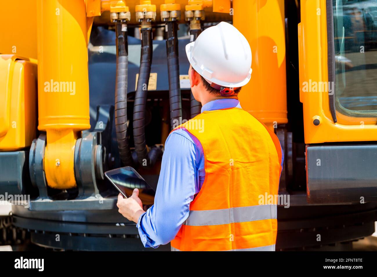 Asian engineer checking plans on construction site Stock Photo - Alamy