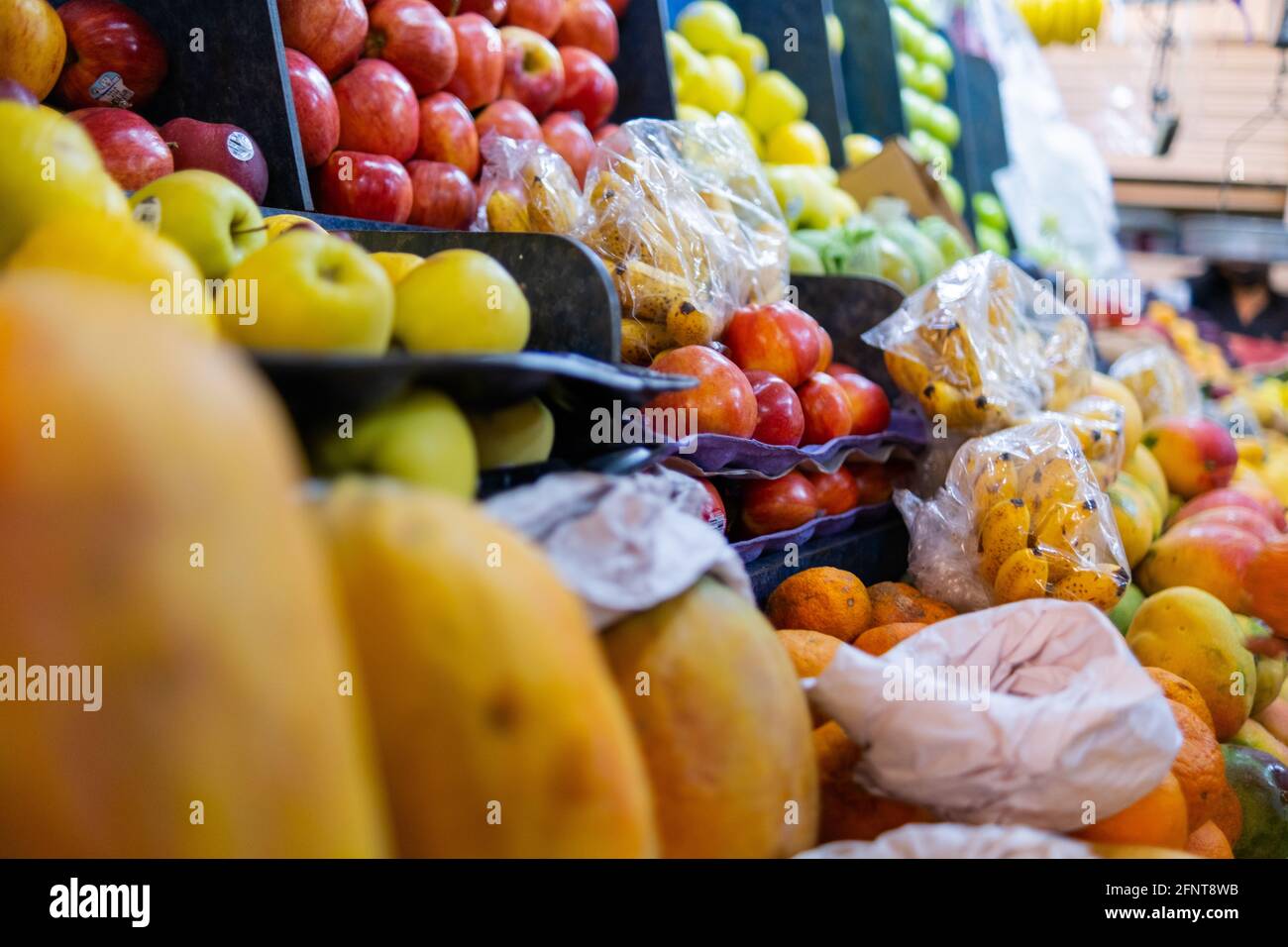 Colorful fruit stand with papayas, tangerines, apples, mangoes and more ...