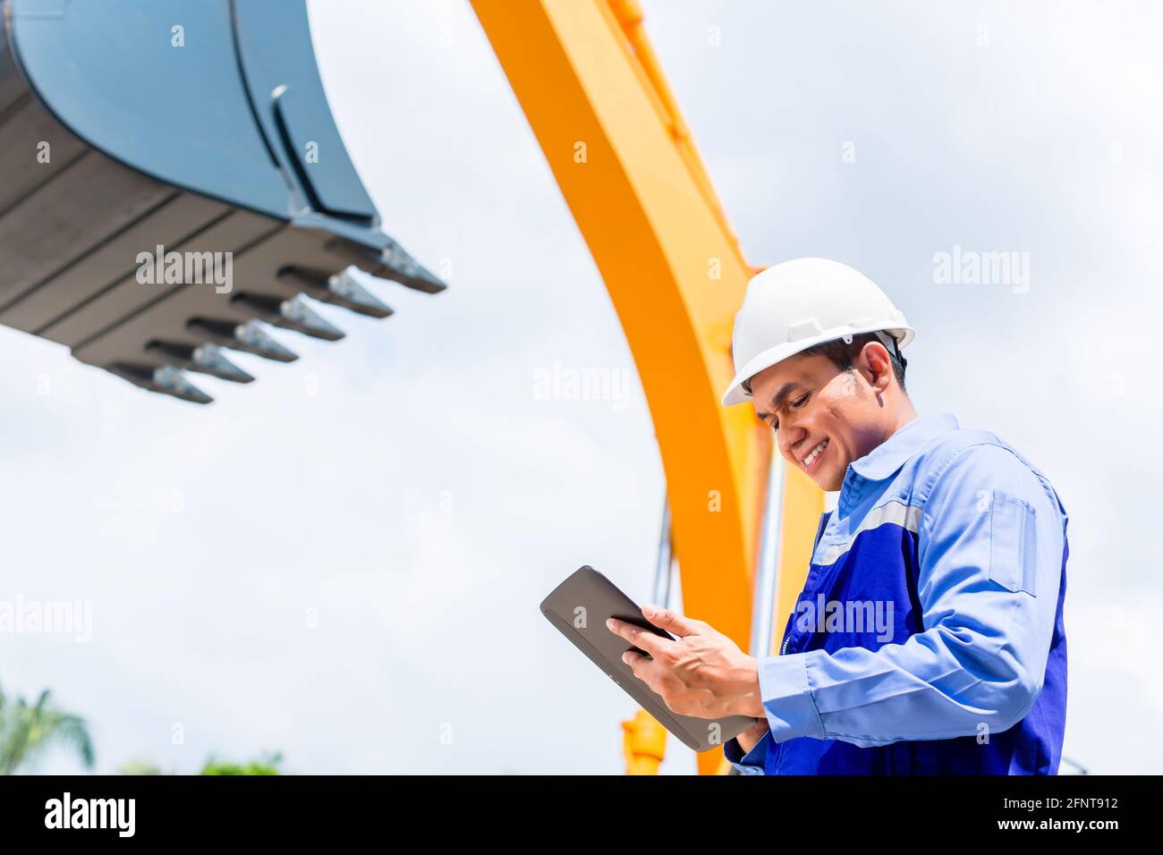 Asian engineer checking plans on construction site Stock Photo - Alamy