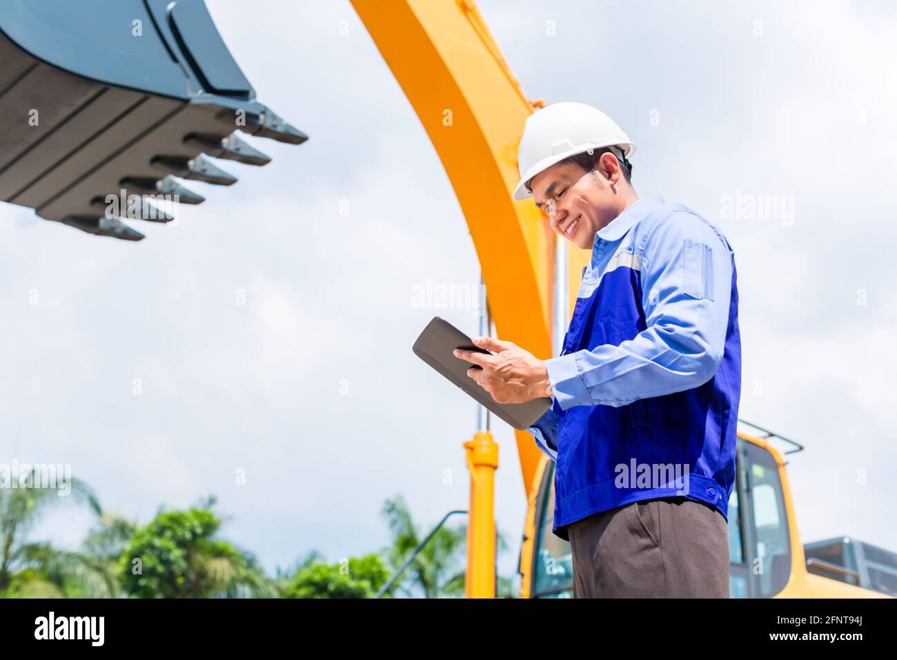 Asian engineer checking plans on construction site Stock Photo - Alamy
