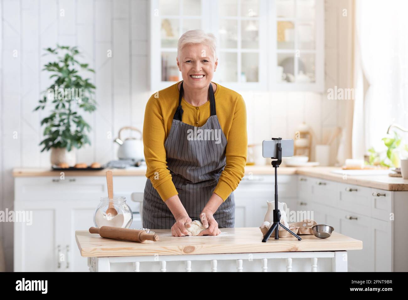 Attractive senior lady cooking at home, watching online class Stock ...