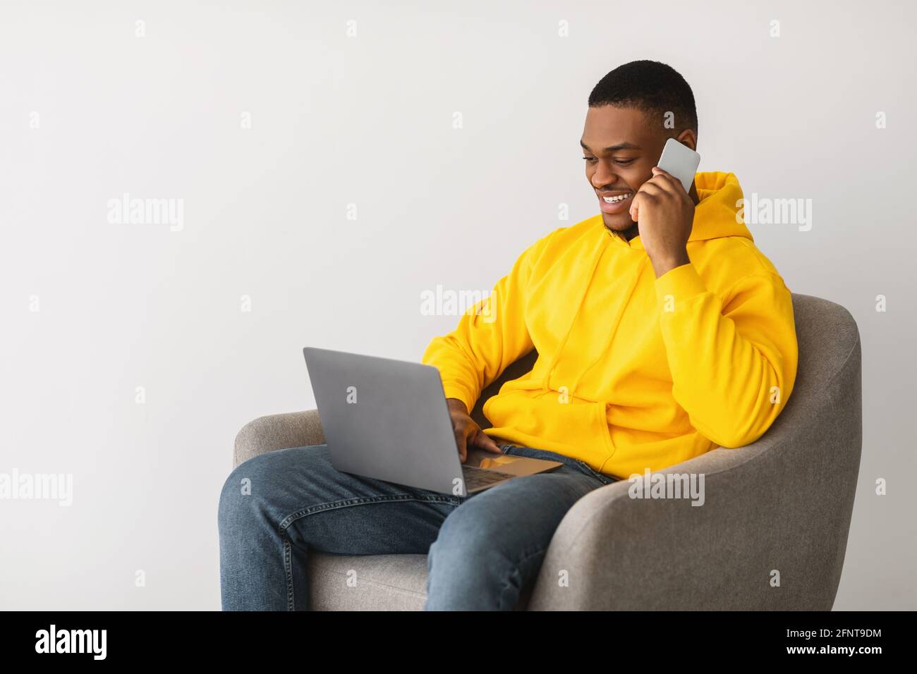 Black Freelancer Guy Talking On Phone Using Laptop, Gray Background ...