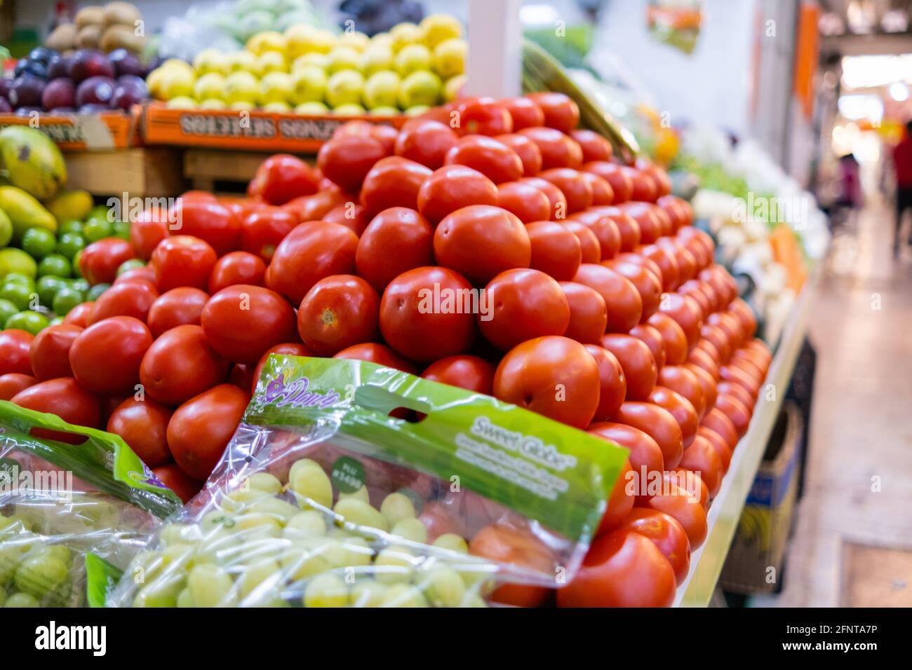 Colorful vegetable and fruit stand with tomatoes, grapes, mangoes, and ...