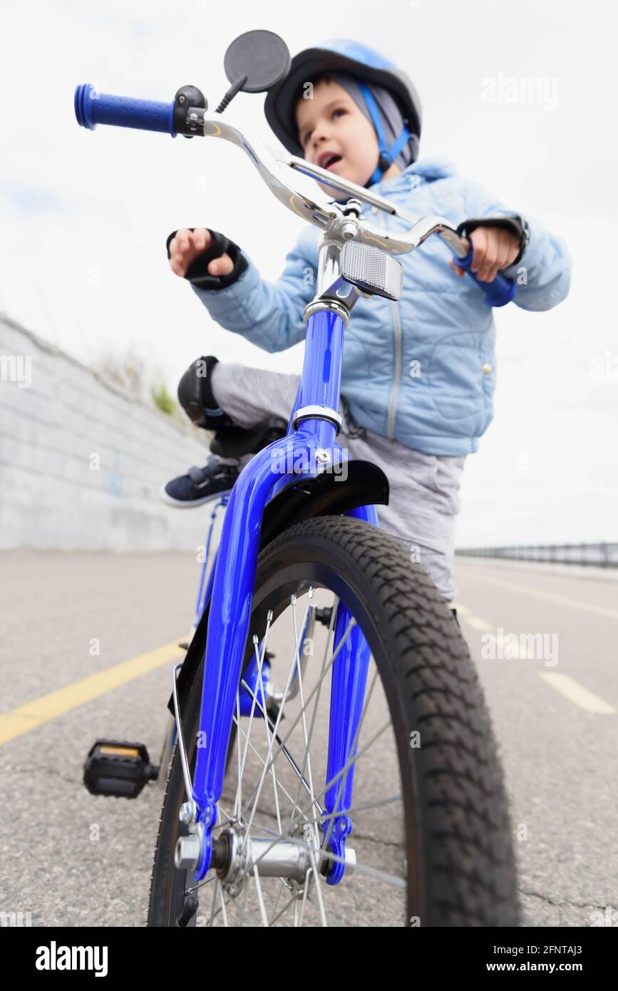 A child in a helmet and protection rides a bicycle on the road Stock ...
