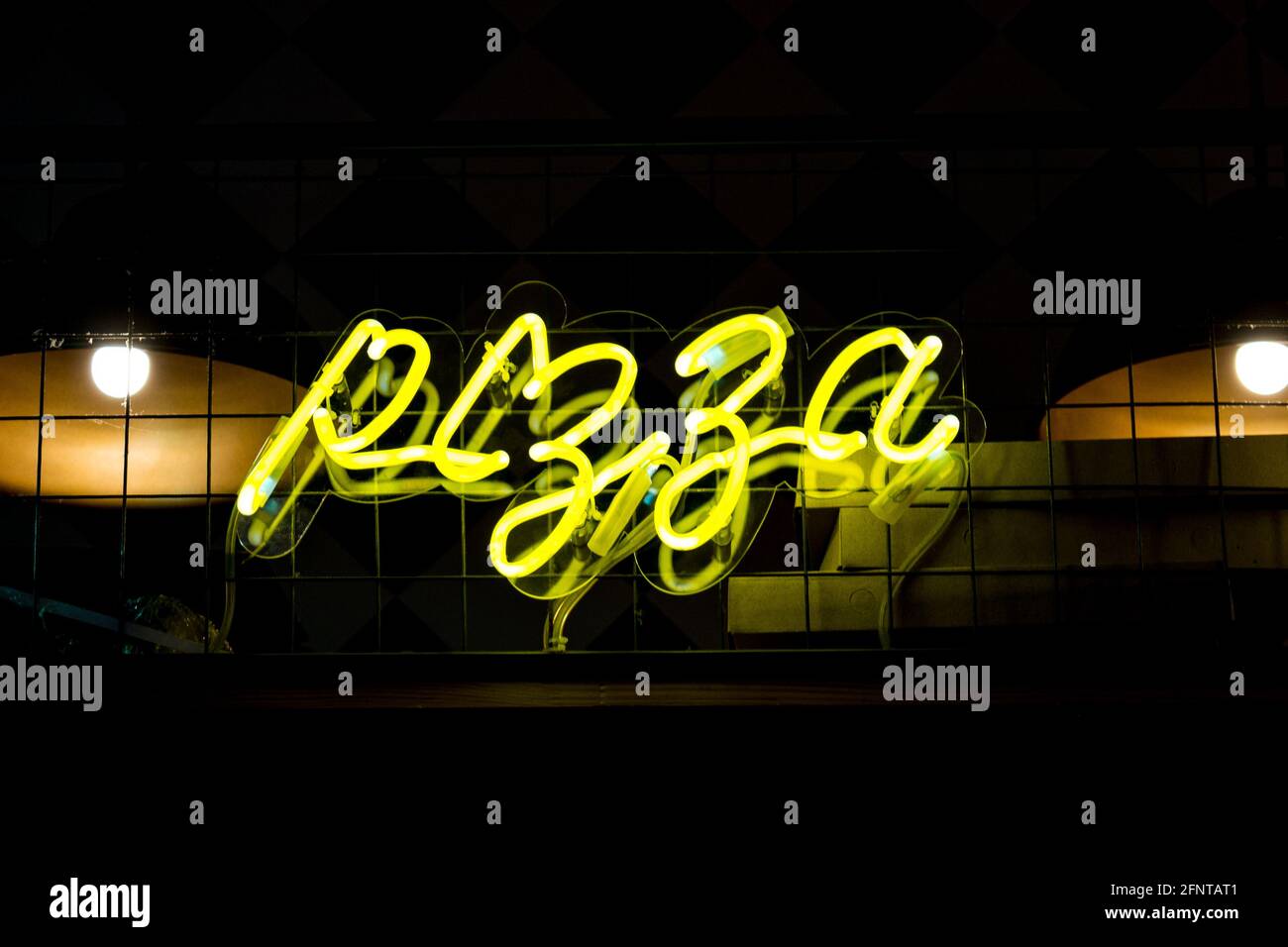 Glowing Neon yellow sign PIZZA and blurred lights on black background ...