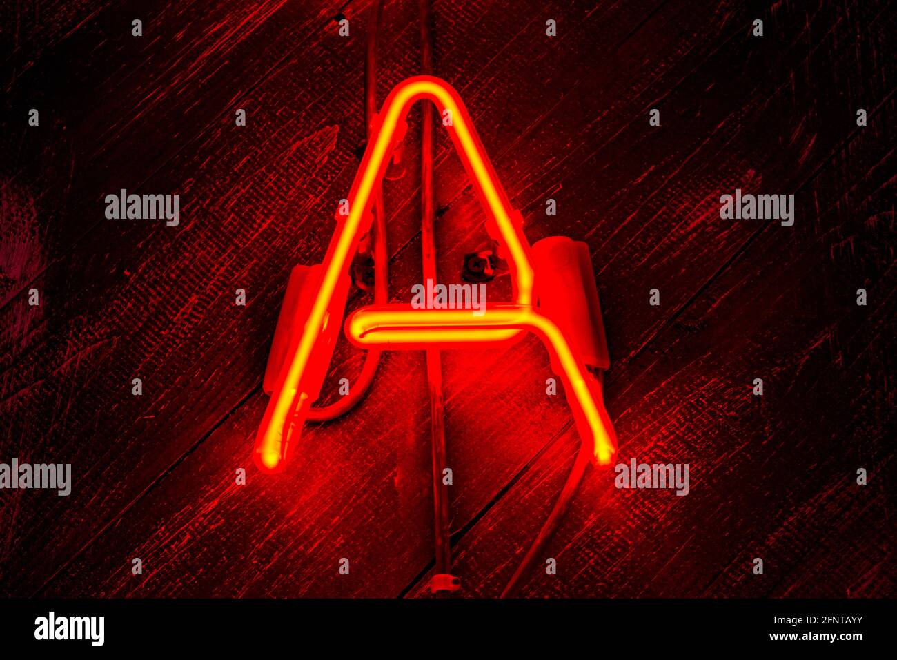 Glowing Neon red letter A on wooden background. Dark tones vintage ...