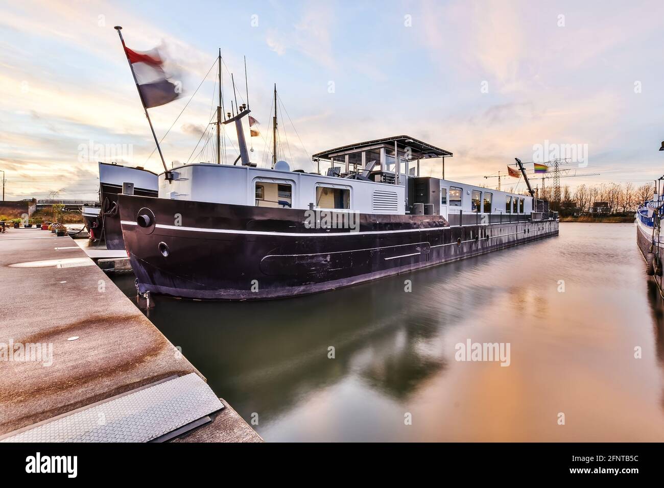 Modern vessel with blurred flag of Netherlands floating near quay on ...