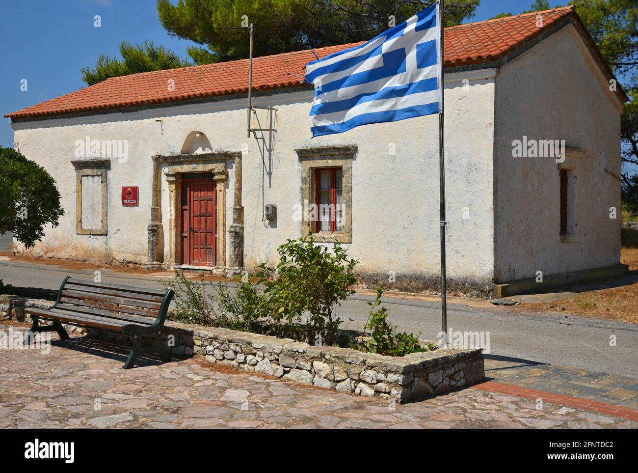 Old municipal building with the weaving Greek flag on the foreground in ...