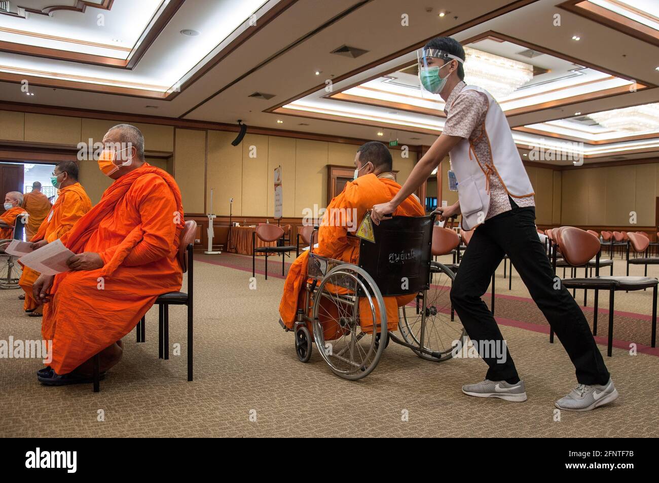 A health worker pushes a wheelchair for a Thai Buddhist monk during a ...
