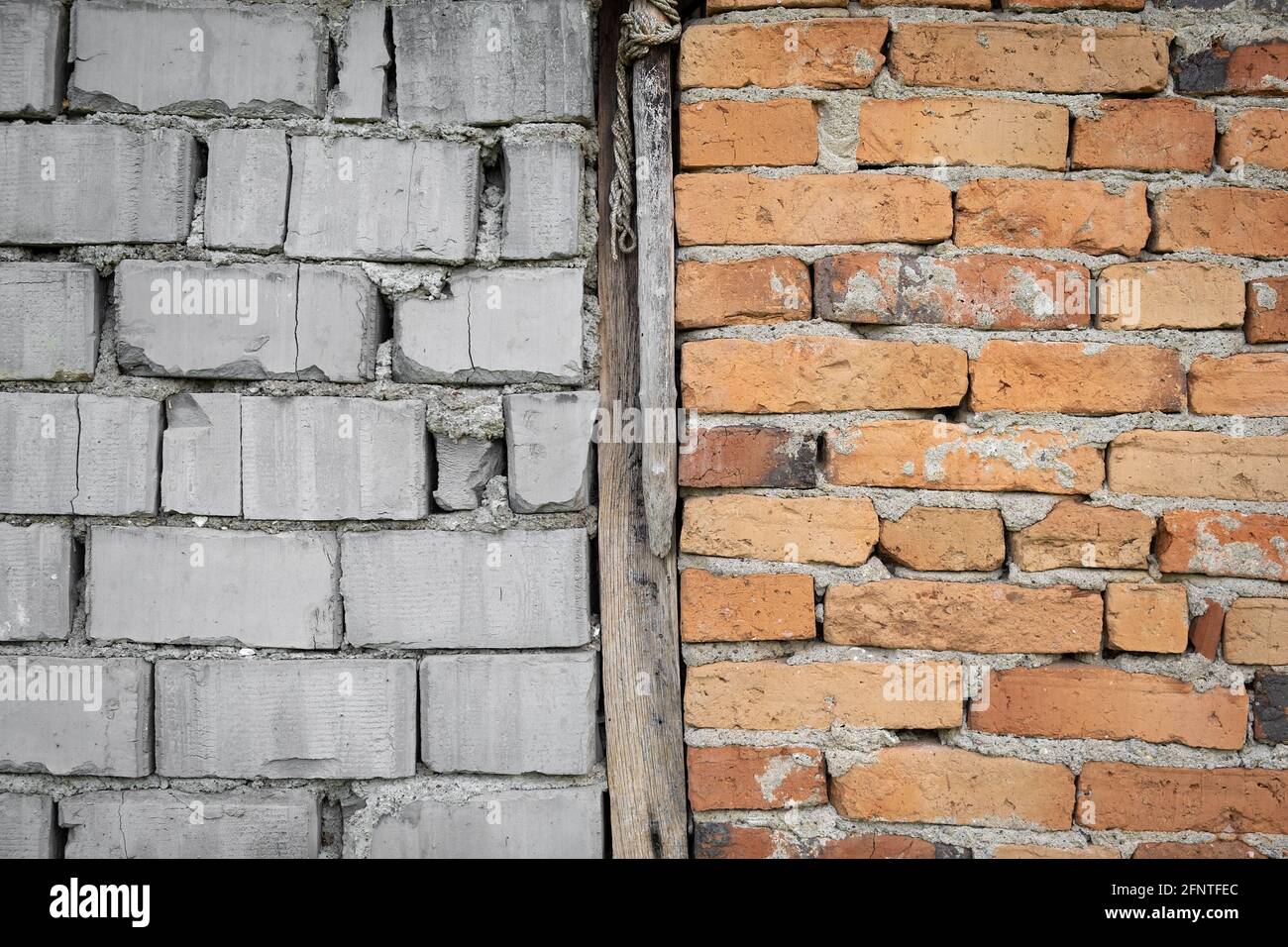 Old wooden beam separating red, rustic brick wall from a wall made from ...