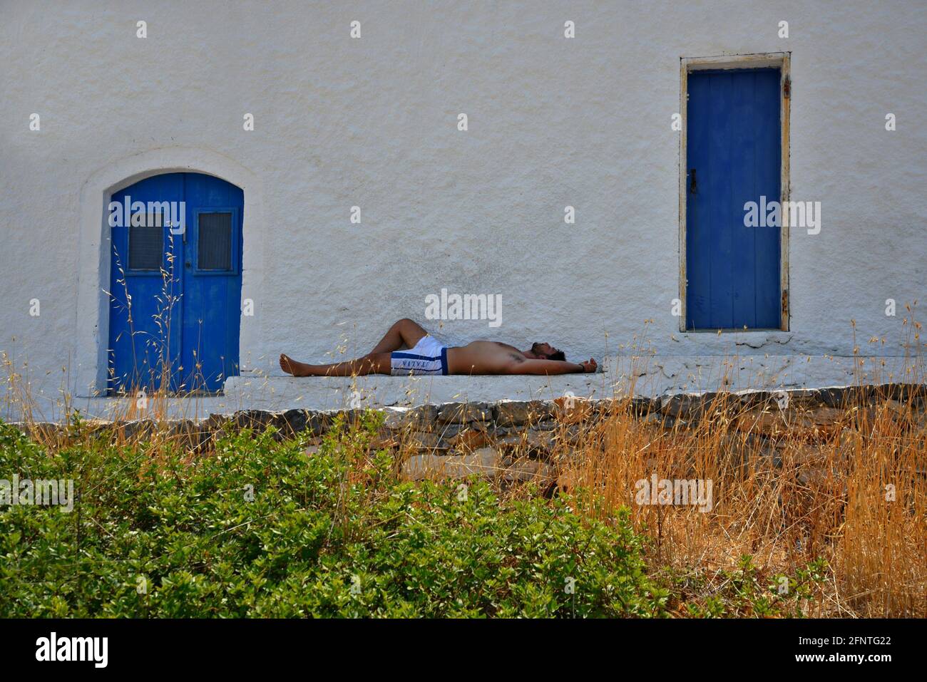 Italian tourist resting at the entrance of a traditional blue and white ...