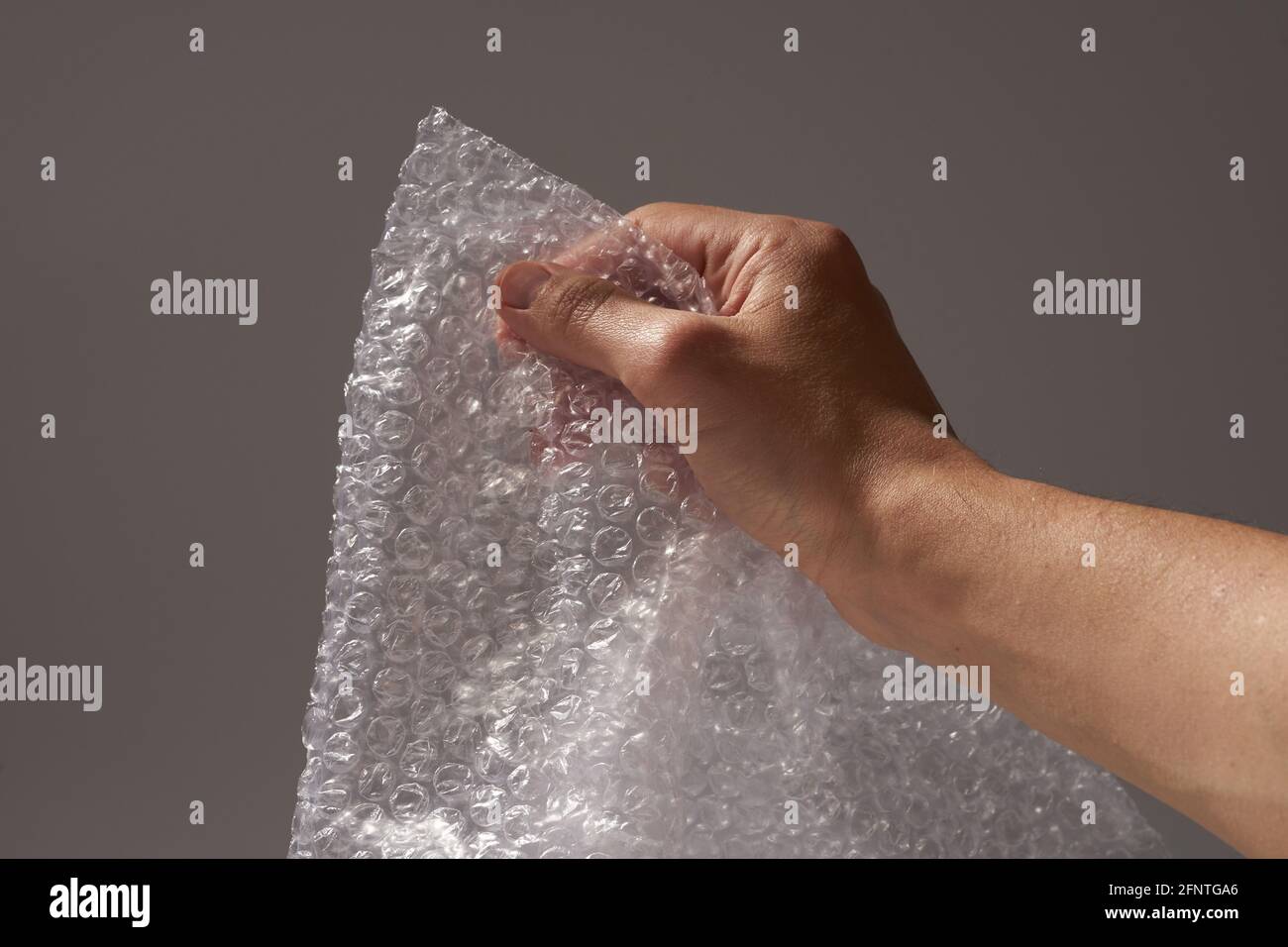 Male hand popping bubbles of bubble wrap on gray background Stock Photo ...