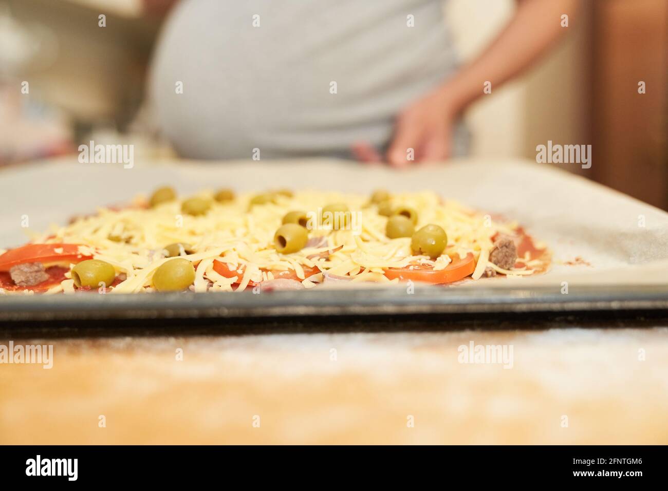 Pregnant woman holds on a baking sheet prepared for baking healthy ...