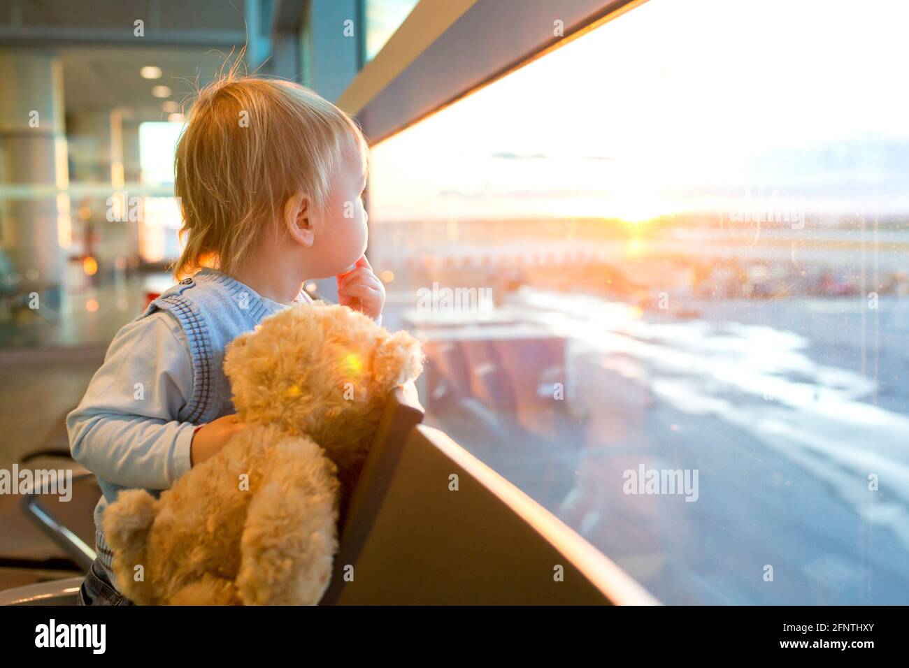 Child, watching from the window of the airport the planes, taking off ...