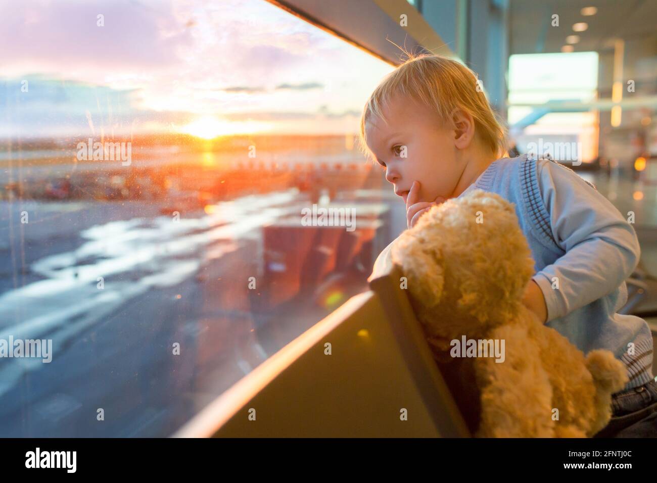 Child, watching from the window of the airport the planes, taking off ...