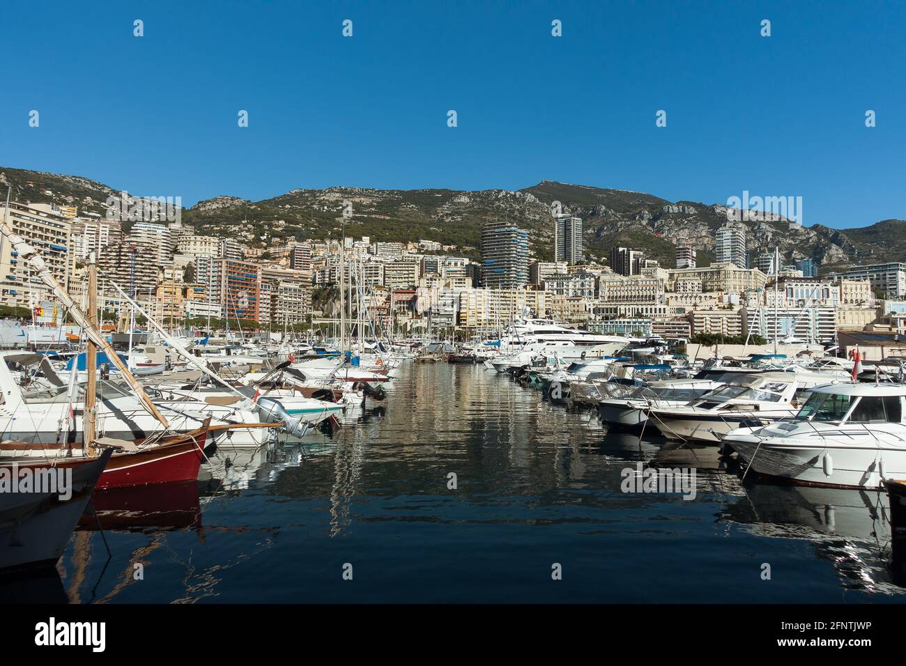 Luxury yachts in the Monaco harbor with large apartment complexes on ...