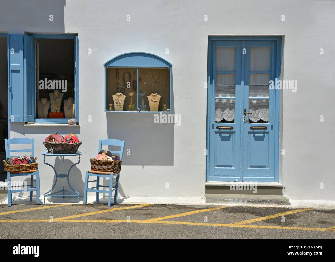 Local souvenir shop facade with a whitewashed wall, blue door a jewelry ...